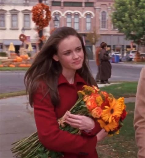 A Woman In A Red Coat Holding Flowers