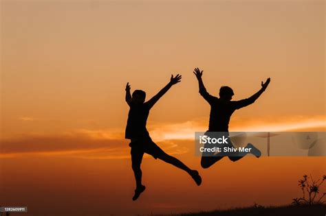 일몰 동안 하늘을 올려 팔을 들고 점프하는 두 인도 친구의 실루엣 우정에 대한 스톡 사진 및 기타 이미지 우정 점프 20