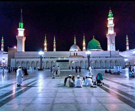 Several People Sitting On The Ground In Front Of A Building With Green