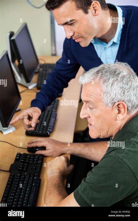Teacher Explaining Senior Man In Computer Class Stock Photo Alamy