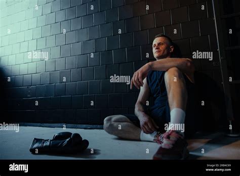 Tired Boxer Resting In Dark Gym After Exercising Near Boxing Gloves On