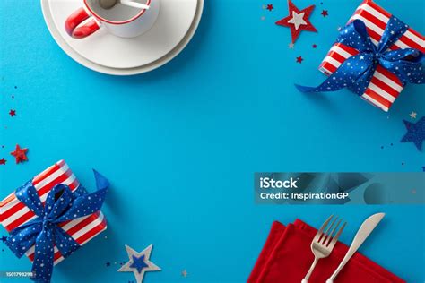 화려한 7 월 4 일 파티를 준비하십시오 접시 식기 컵 냅킨 별 색종이 리본 리본이 달린 선물 상자가 있는 탑 뷰 테이블 텍스트 또는 광고를 위한 빈 프레임이 있는 파란색