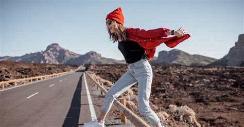 화창한 날 화산 계곡을 여행하며 도로에서 점프하는 빨간 옷을 입은 젊은 여성의 라이프스타일 초상화 평온한 라이프 스타일과 여행 개념 사진 Unsplash의 기쁨 이미지