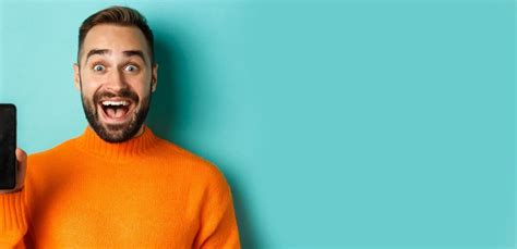 Gros Plan Dun Beau Mec Barbu En Pull Orange Montrant Lécran Du