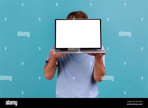 Portrait Of Unknown Man Hiding Face Behind Laptop With White Empty Display And Presenting New