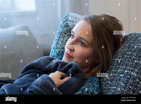 A Young Woman Lies Cuddled Up In A Blanket On A Sofa In Dorfen Bavaria