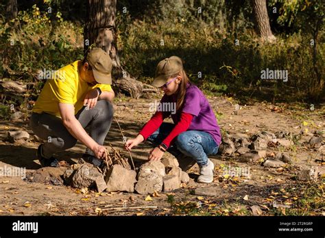 Dad And Daughter Make Fire Outdoors To Cook Food On Camping Trip