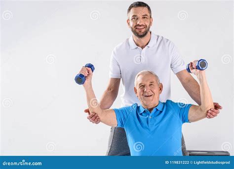 Portrait Of Smiling Rehabilitation Therapist Assisting Senior Man
