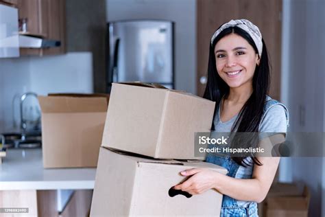 새 아파트로 이사하는 젊은 아름다운 여성이 상자를 들고 카메라를 마주 보며 웃는 모습 라틴 아메리카 히스패닉 민족에 대한 스톡 사진 및 기타 이미지 라틴 아메리카