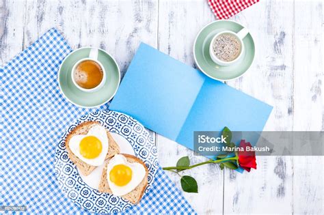 꽃 향기로운 커피와 연인 들의 낭만적인 아침에 대 한 심장모양의 토스트의 2 개의 컵 빨간 장미 편지 또는 메모 테이블에 발렌타인의 날 어머니의 날의 개념 플랫이 하다