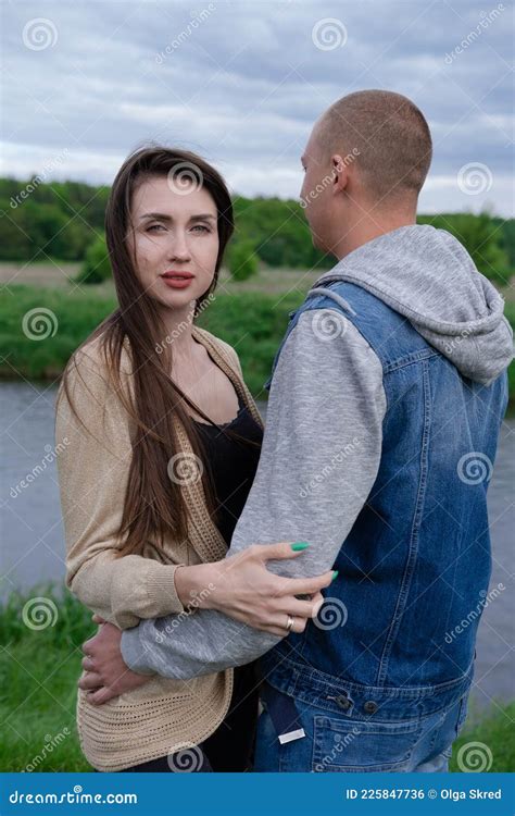 Happy Young Couple Outdoors Near Lake And Green Grass Bald Man And