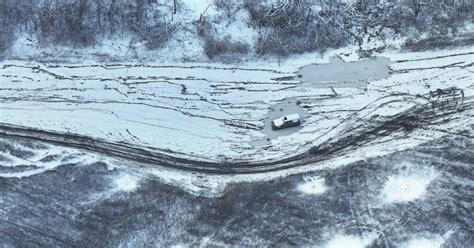 눈 쌓인 포탄 구덩이 주변에 버려진 자동차