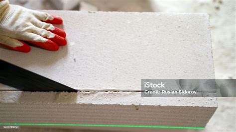 쇠톱을 사용하는 건축업자는 폭기 된 콘크리트 블록을 자릅니다 건설 계약자는 오토클레이브 폭기 콘크리트 블록 폭기 콘크리트를 건설 현장에서 손으로 볼 수 있도록 절단합니다