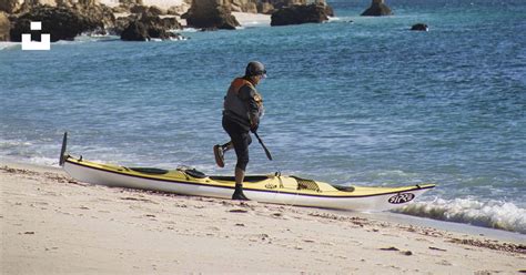 Un Homme Debout Sur Une Planche De Surf Sur Une Plage Photo Image