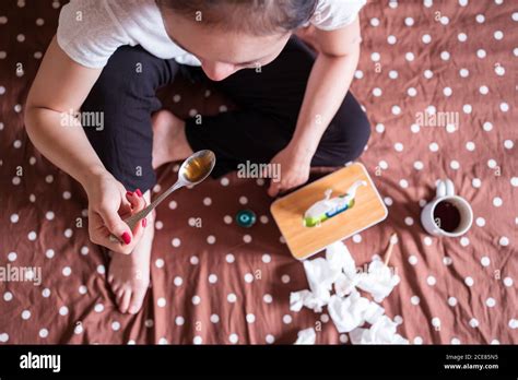 From Above Unrecognizable Sick Female Sitting On Bed In Apartment And