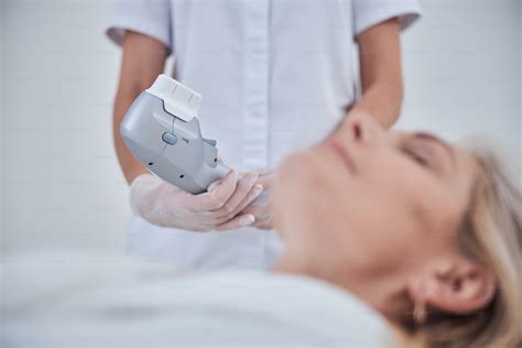 의사가 미용 클리닉의 여성 환자 근처에 서 있는 동안 의사의 손에 현대 초음파 기계의 초상화를 닫습니다 사진 Unsplash의 미용사 이미지