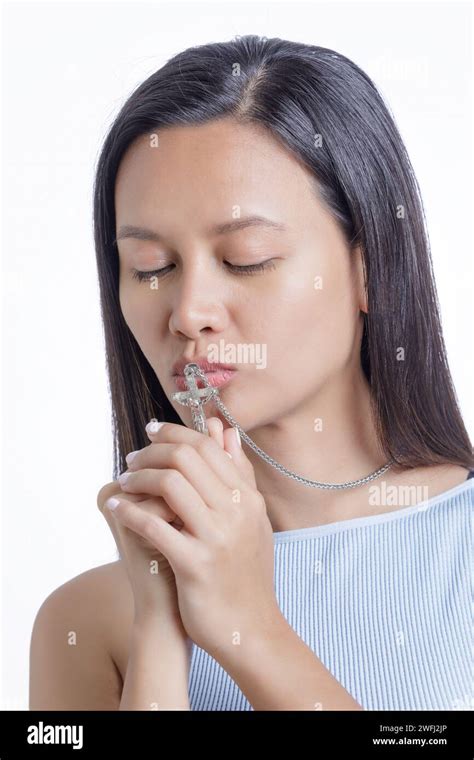 Young Catholic Asian American Praying With A Crucifix On A White
