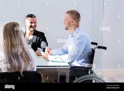 Disabled Male Manager Sitting With His Colleagues At Workplace Stock