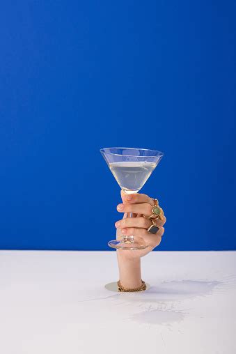 파란 색으로 분리된 마티니 칵테일 잔을 들고 있는 팔찌와 반지가 있는 여성의 자른 전망 칵테일에 대한 스톡 사진 및 기타 이미지 칵테일 인간 손 유색 배경 Istock