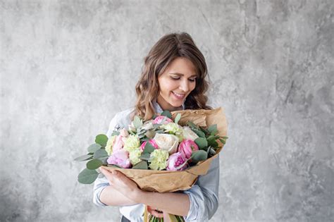젊은 여자는 그의 손에 아름 다운 꽃다발을 보유 하고있다 화 초 재배 자 꽃이 게에서 아름 다운 부케 만들기 여자 도우미 또는 꽃 디자인 스튜디오 소유자입니다 구도에 대한