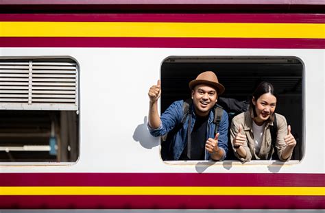 신혼 여행에 가방을 가진 커플 아시아 여행자 기차로 여행 창문 밖으로 머리를 찌르십시오 플랫폼 기차역 근처의 행복한 남자와 여자 휴가 시간 휴일 주말에 관광 계획 2명에