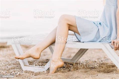 여성의 다리를 클로즈업한 한 여성이 모래 사장에서 바다에 누워 서서 긴 길에 앉아 있었다 여름 방학 바다 귀여운에 대한 스톡
