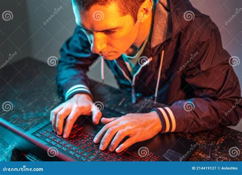 A Male Hacker Is Typing On A Laptop Keyboard In A Dark Room Under A Neon Light Cybercrime Fraud