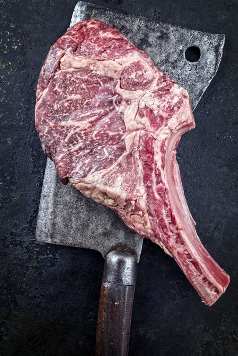 Raw Dry Aged Wagyu Tomahawk Beef Steak On An Old Rustic Kitchen Cleaver