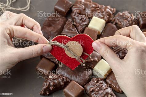 식욕을 돋우는 음식 배경 여성의 손에 발렌타인 데이 초콜릿 수제 사탕과 레드 하트 카드의 구색 초콜릿 배경 검은색에 대한 스톡
