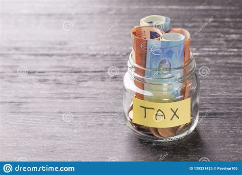 Glass Jar On A Black Wooden Table With Coins And Euro Banknotes And The