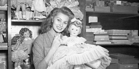 An Old Photo Of A Woman Holding A Doll In Her Arms And Posing For The