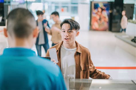 영화 관람권과 팝콘을 구매하는 아시아 계 중국 젊은 남성 관객이 영화관 영화관에서 상영 시간 전에 비접촉식 결제를 마신다