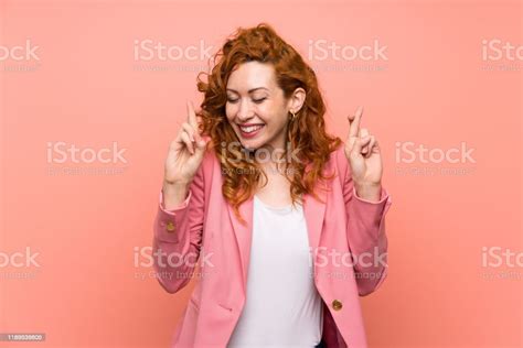 빨간 머리 여자 에 정장 위에 고립 된 핑크 벽 와 손가락 교차 머리 모양에 대한 스톡 사진 및 기타 이미지 머리 모양
