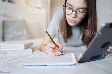 귀여운 십대 소녀 사용 태블릿 거짓말 에 침대 에 집 12 13세에 대한 스톡 사진 및 기타 이미지 12 13세 Covid
