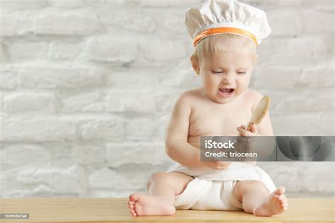 아기 요리사요리사 모자와 나무로 되는 숟가락 사랑 스러운 아기의 실내 초상화 가정 주방에 대한 스톡 사진 및 기타 이미지