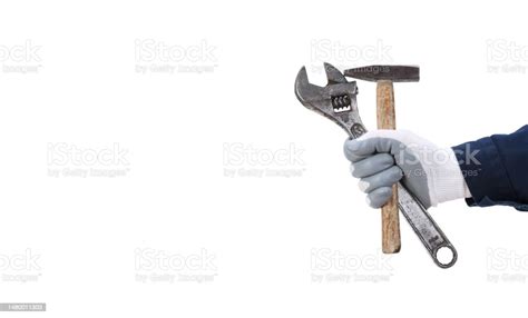 보호 장갑을 낀 작업자의 손에는 흰색 배경에 크고 오래된 조정 가능한 렌치와 망치가 들어 있습니다 갈색에 대한 스톡 사진 및