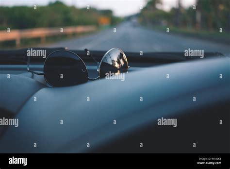 Sunglasses On Car Panel With View Of Road Background While Traveling On