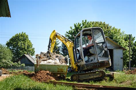 민스크 벨라루스 2024년 5월 24일 미니 굴삭기는 토양에 도랑을 파고 있습니다 굴삭기 운전자가 버킷을 제어합니다 크롤러 머신 토공 장비 굴착 건설 현장에서 굴착 작업