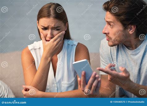 Husband Showing Cheating Wife Her Phone Sitting On Sofa Indoor Stock