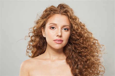 웨이브 머리와 자연스러운 메이크업을 한 화려한 여성 긴 곱슬 머리와 신선한 맑은 피부를 가진 패션 모델 흰색 배경에 포즈를 취