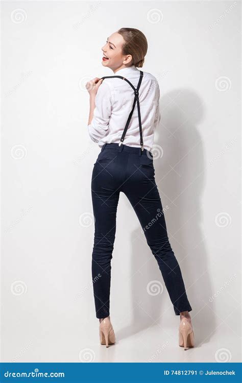 Fashion Model In Black Trousers And Top Posing Over White Back View