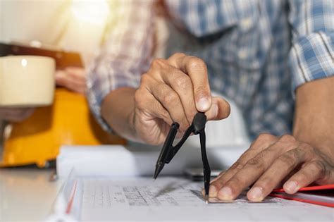 건설 현장 건설 산업 엔지니어링 비즈니스 컨셉의 회의실 사무실에서 책상에 청사진에 디바이더 나침반이 있는 전문 건축가 또는 인테리어 디자이너 핸즈 드로잉 개념에 대한 스톡