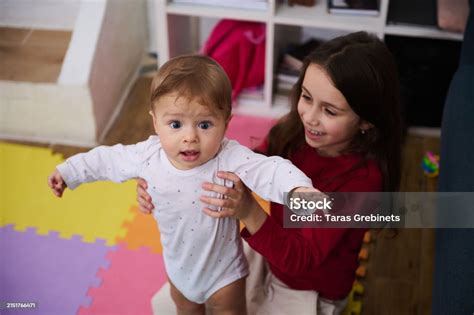 사랑스럽고 돌보는 여동생의 손에 있는 아름다운 사내아이 첫 걸음을 내딛는 오빠를 응원하는 귀여운 아이 소녀 유아기와 아기 시절 행복한 가족 관계 지원 함께 시간 보내기 2