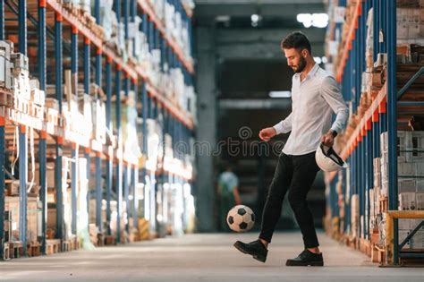 Kicking Soccer Ball Storage Worker Is In The Warehouse With Bunch Of