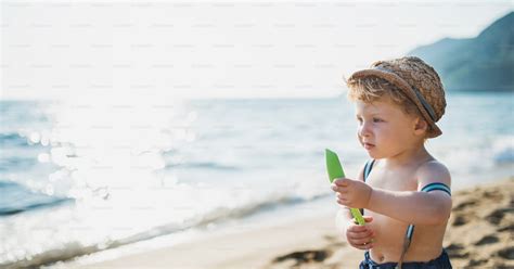 여름 휴가에 해변에 서서 모자와 반바지를 입은 작은 유아 소년이 삽을 들고 있습니다 공간을 복사합니다 사진 Unsplash의 기쁨 이미지