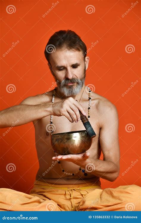 Elderly Yogi Male With Naked Torso In Brown Pants Is Practicing Yoga Lying On The Floor