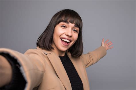 灰色の背景の上に孤立した立ってコートを着て自分撮りを取る陽気な若い女性 ウクライナのストックフォトや画像を多数ご用意 ウクライナ
