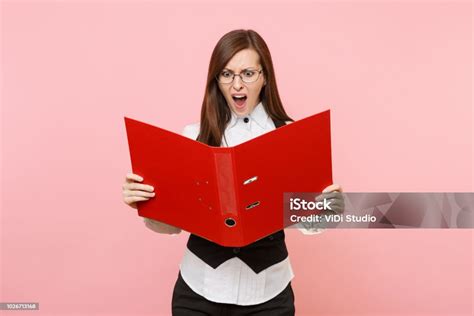 파스텔 핑크 배경에 고립 된 종이 문서에 대 한 빨간색 폴더에 안경 비명에 젊은 화가 비즈니스 여자 여자 보스입니다 성과 경력