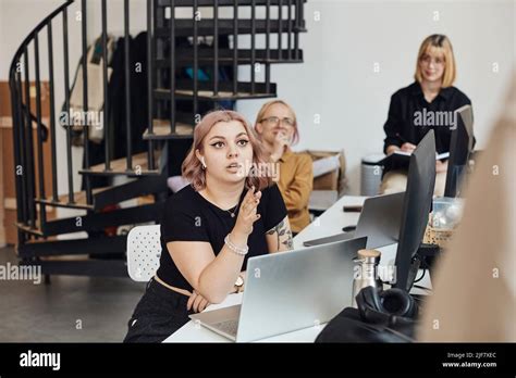 Young Female Computer Programmer Discussing With Colleague During