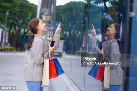 쇼핑몰에서 쇼핑백과 스마트폰을 들고 있는 여성 쇼핑센터에서 행복한 쇼핑 Brand Name Mobile Payment에 대한 스톡 사진 및 기타 이미지 Brand